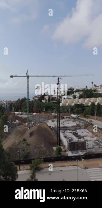 An aerial view of a large construction site with cranes and workers ...