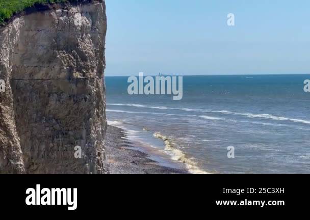 Majestic white chalk cliffs tower above a calm blue sea, creating a ...