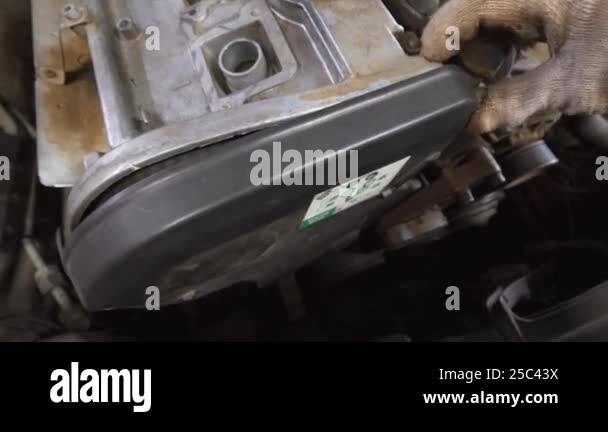 Mechanic's hands remove plastic cover, exposing timing belt, tensioner ...