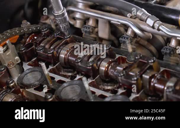 Mechanic tightening bolts on car engine's camshaft cover using socket ...