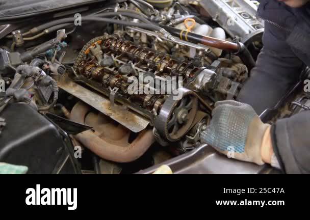 Mechanic uses wrench to turn camshafts and they press on valves on open ...