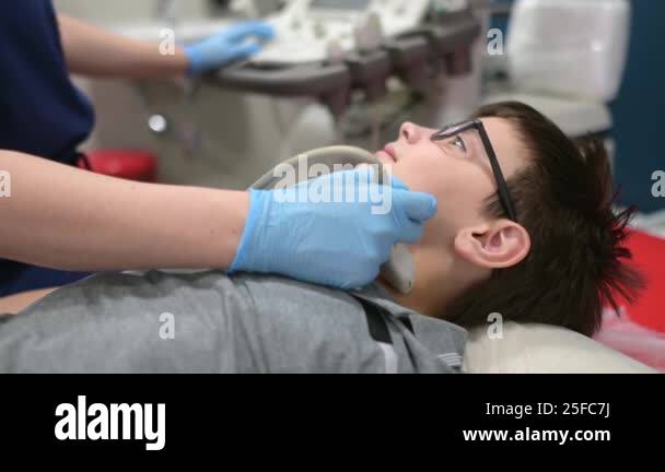 Doctor making ultrasound of thyroid gland for boy using scanner machine ...