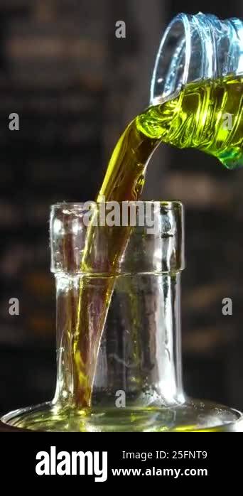 Close up of male hand pouring olive oil from glass bottle in slow ...