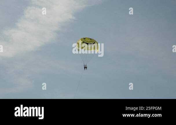 A couple enjoys parasailing high in the sky with a bright smiley face ...