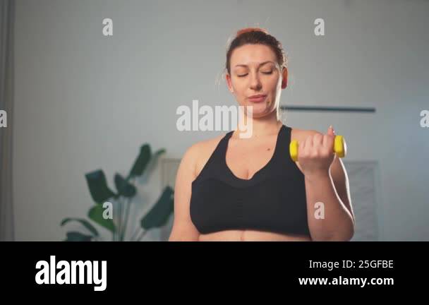Fitness workout training. Woman picking up dumbbells. Plus size female ...
