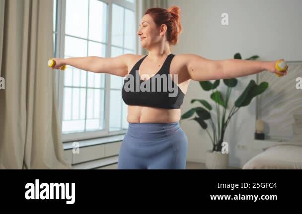 Fitness workout training. Woman picking up dumbbells. Plus size female ...