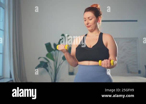 Fitness workout training. Woman picking up dumbbells. Plus size female ...