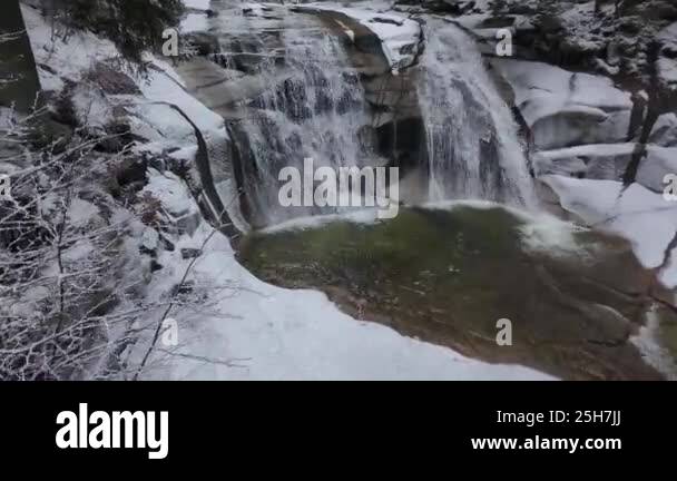 A stunning view of a waterfall cascading over snowcovered rocks in a ...