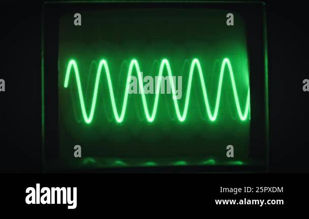 Green sine wave pattern dances on a vintage oscilloscope screen against ...