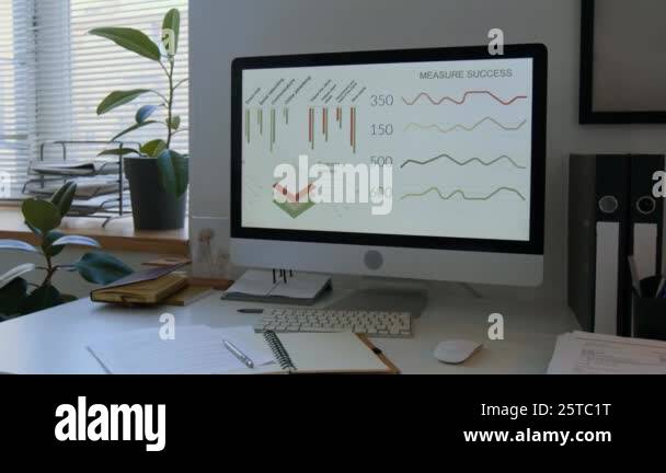 Office desk with desktop computer displaying business success metrics ...
