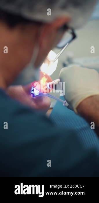 A dentist uses specialized tools to perform an oral procedure on a ...