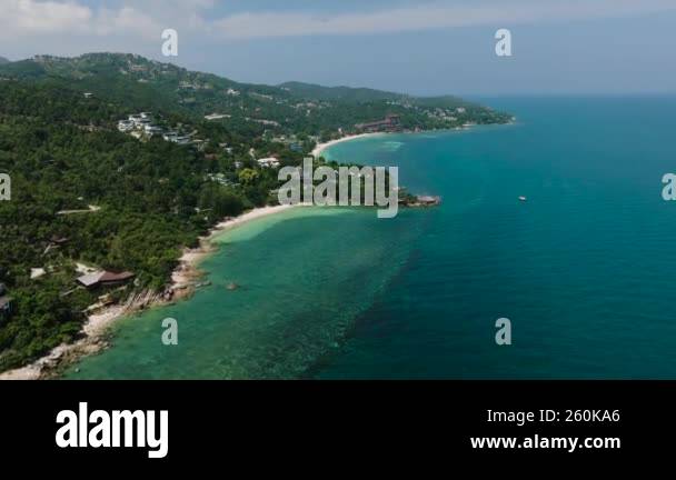 White sandy beaches along a vibrant coastline with lush green hills in ...