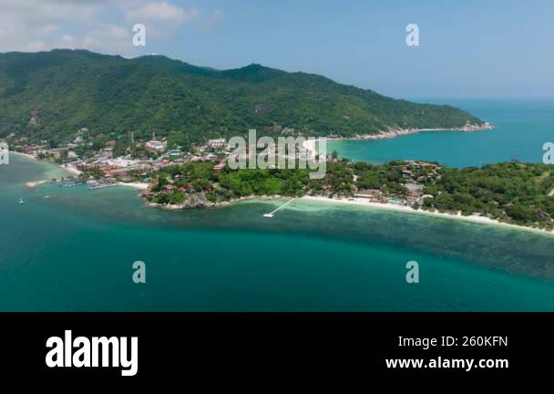 Small village nestled amidst dense greenery along a clear blue ...