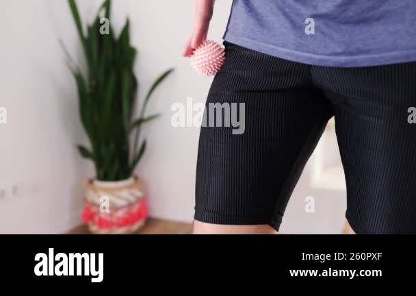 Athlete using a spiky massage ball for releasing muscle tension in legs ...