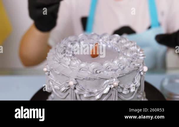 A chief puts nuts and candies on a creamy cake in a restaurant, close ...