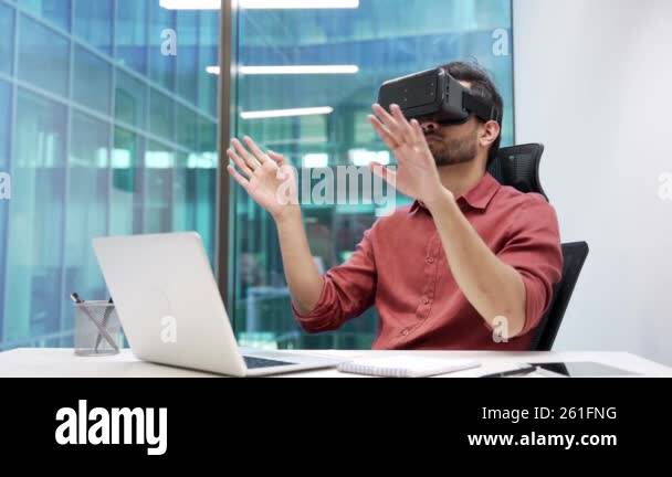 Successful businessman works using VR glasses in virtual reality simulator sitting at workplace ...