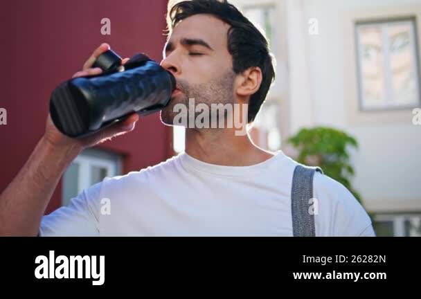 Man drinking water bottle outdoors at sunlight closeup. Handsome ...