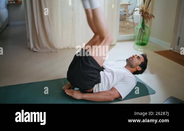 Athletic guy lifting legs lying on yoga mat performing fitness exercise ...