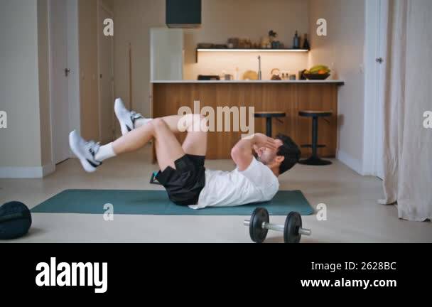 Active sportsman training abs on fitness mat home. Energetic young ...
