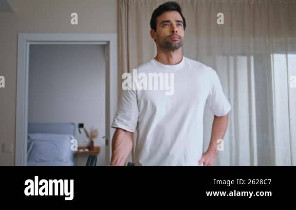 Muscular guy lifting dumbbells in light modern apartment closeup ...
