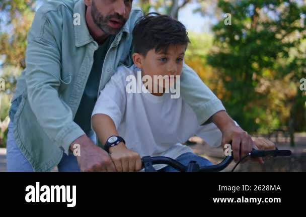 Little boy and father riding cycle at summer sunny urban park closeup ...