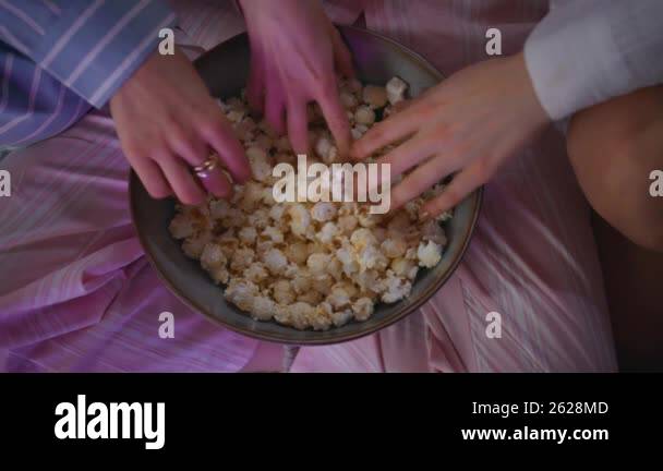 Friends fingers grabbing popcorn from bowl at home pajamas party ...