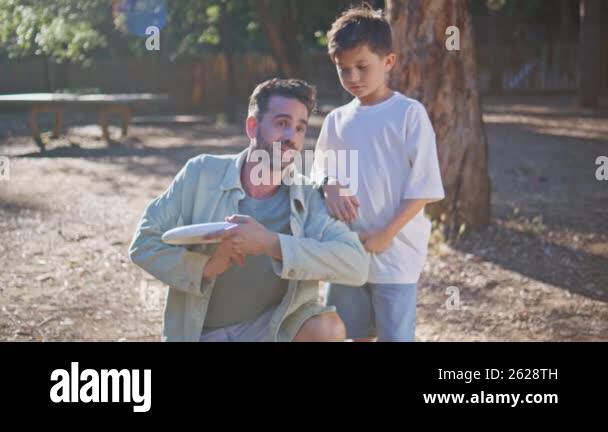 Dad explaining frisbee game rules to small child at sunny forest ...