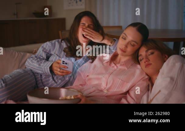 Tired woman lying couch in pajamas yawning at sleepover with friends ...