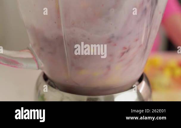 Blending a smoothie of various fruits inside a blender with milk, in a ...