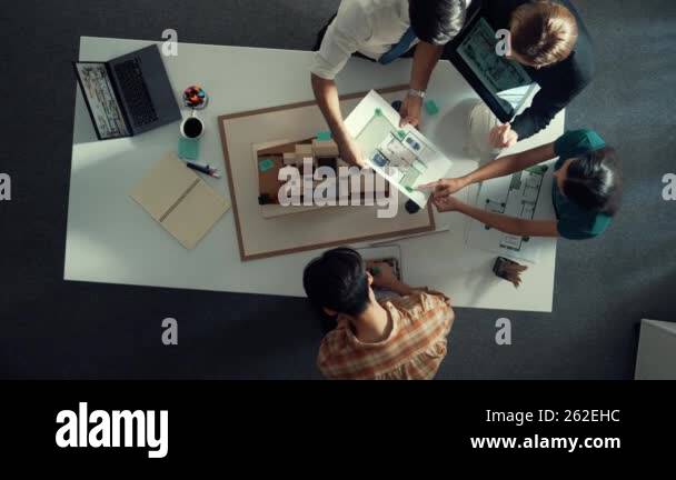 Top down view of manager pointing at house model and explain building ...