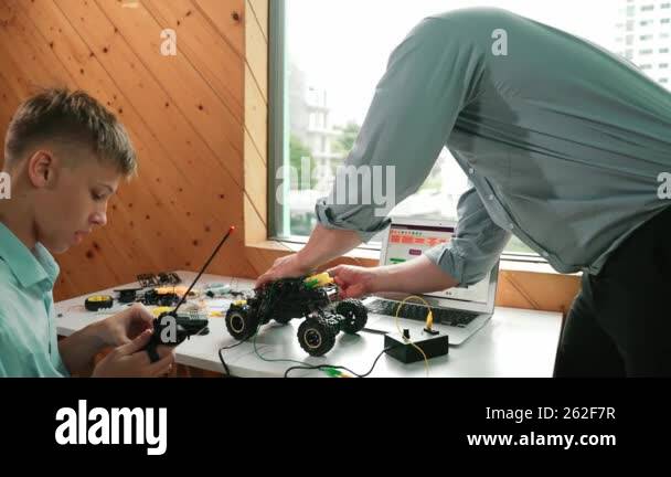 Skilled teacher help young student fixing car model at STEM class ...