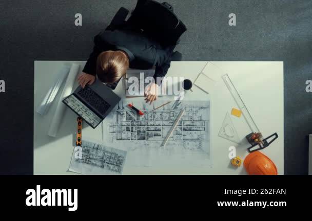 Aerial view of architect drawing while working at laptop. Top down view ...