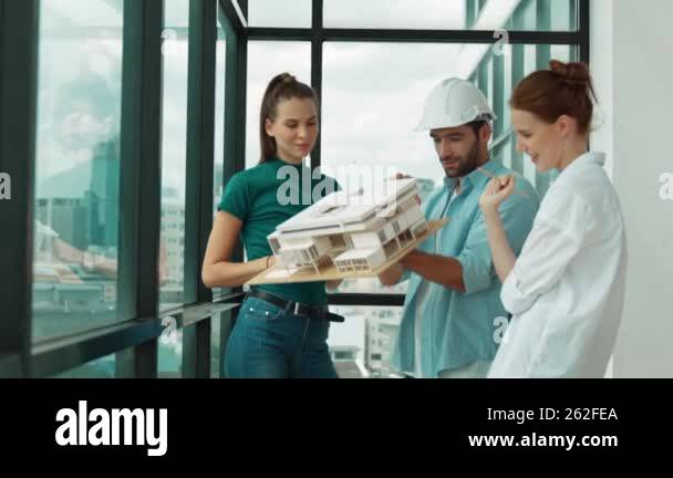 Project manager holds house model while architect engineer team share ... Project manager holds house model while architect engineer team share ...
