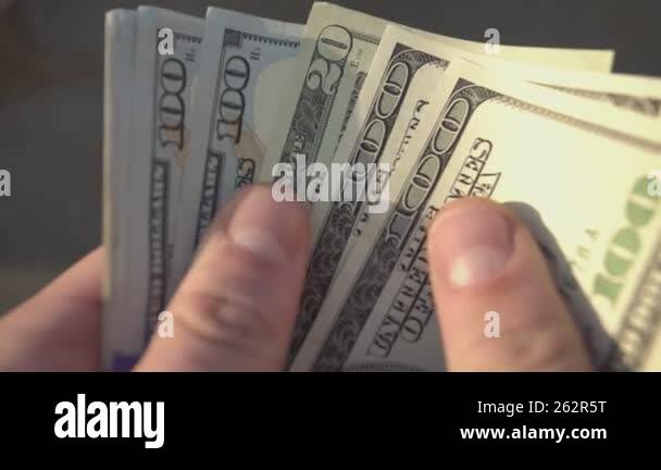 Milan, Italy 1 January 2025: Man counts a stack of us dollar bills ...
