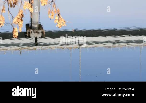 Reflection in river of bridge with man walking along it and passing ...