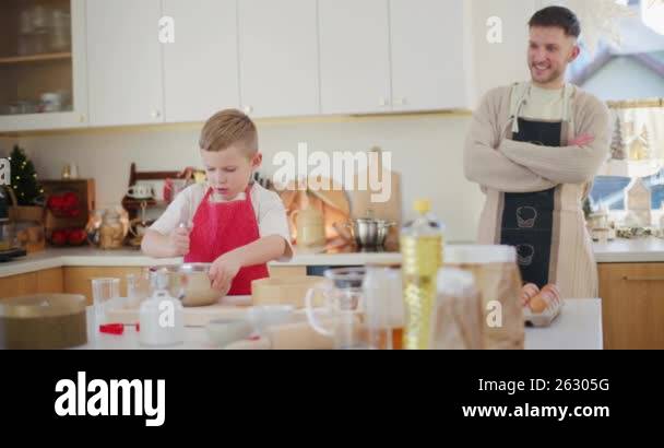 A father proudly watches his son cook in the kitchen, admiring his ...