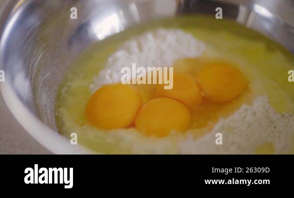 Several raw eggs sit cracked in a bowl of flour, ready for mixing Stock Video Footage - Alamy