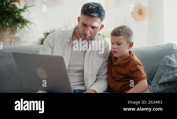 A young boy and his dad spend time together on the computer, sharing ...