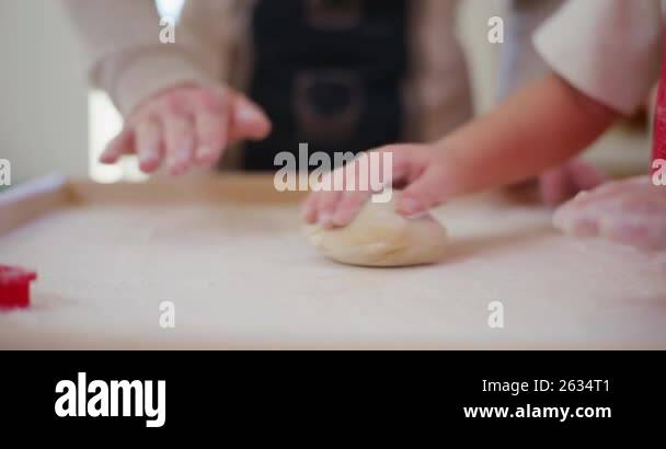 A father patiently teaches his son how to knead and shape bread dough ...