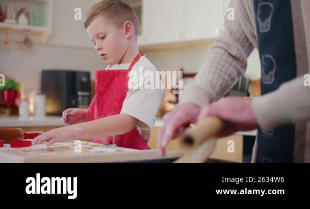 A young boy eagerly helps his father make gingerbread cookies, enjoying ...