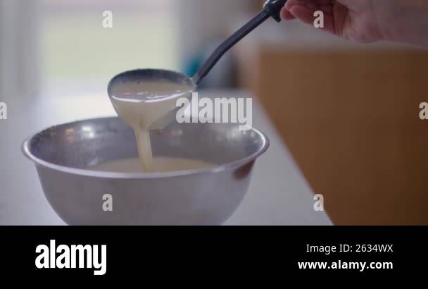 A woman pours pancake batter into a pan using a ladle Stock Video ...