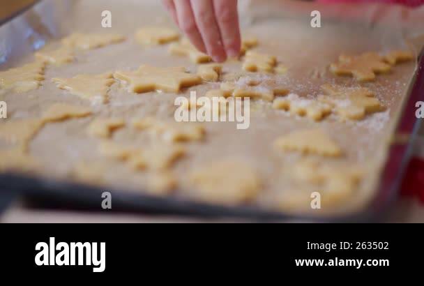 A detailed view of a young boys hand sprinkling sugar on fresh cookies ...