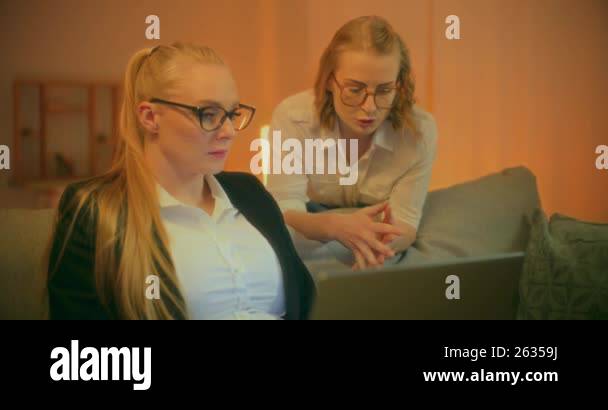 Two friends work together on a laptop late at night, enthusiastically ...