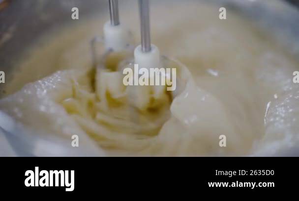 A close-up of mixer blades blending pancake batter smoothly in a metal ...