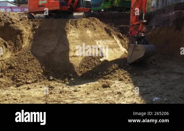 Low view on excavator's work tool, blade as digging, excavating foundation for new residential ...