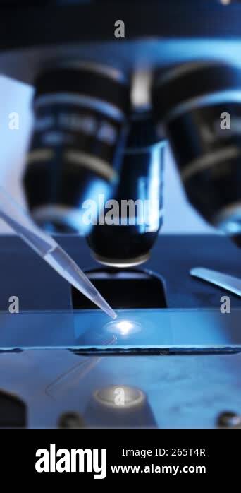 A scientist in white gloves pipettes a sample of liquid onto the glass ...