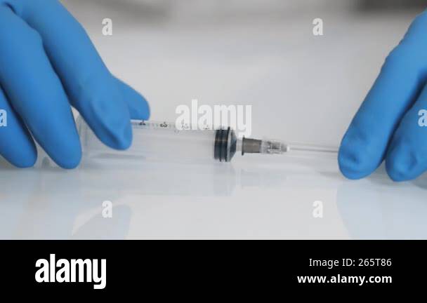 Close-up of hands in blue protective gloves taking a syringe and ...