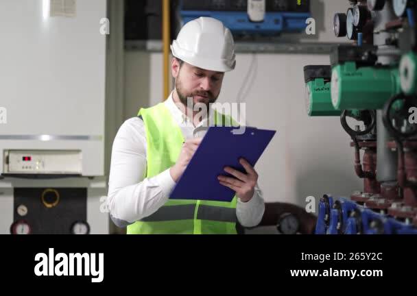 Caucasian male engineer in boiler room inspecting heating system ...