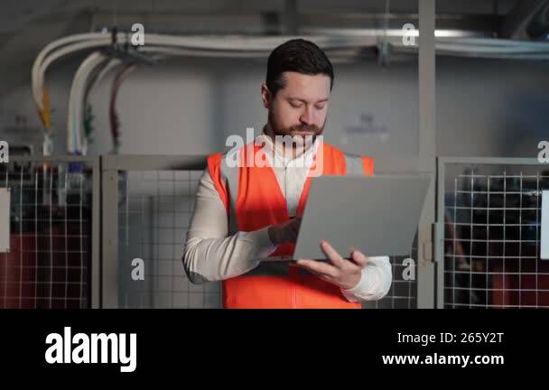 Serious electrical engineer with a beard and wearing an orange safety ...