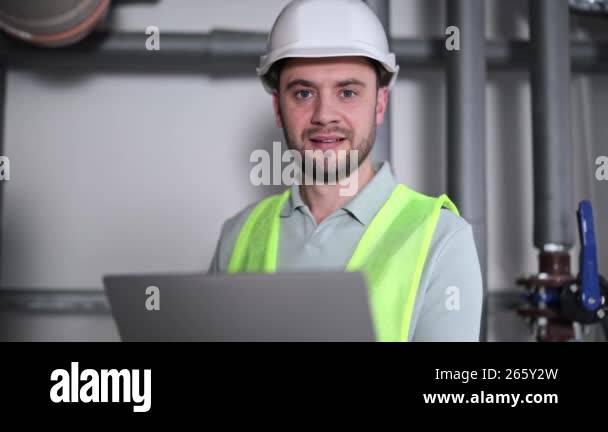 Smiling industrial engineer with laptop in boiler room. Confident ...